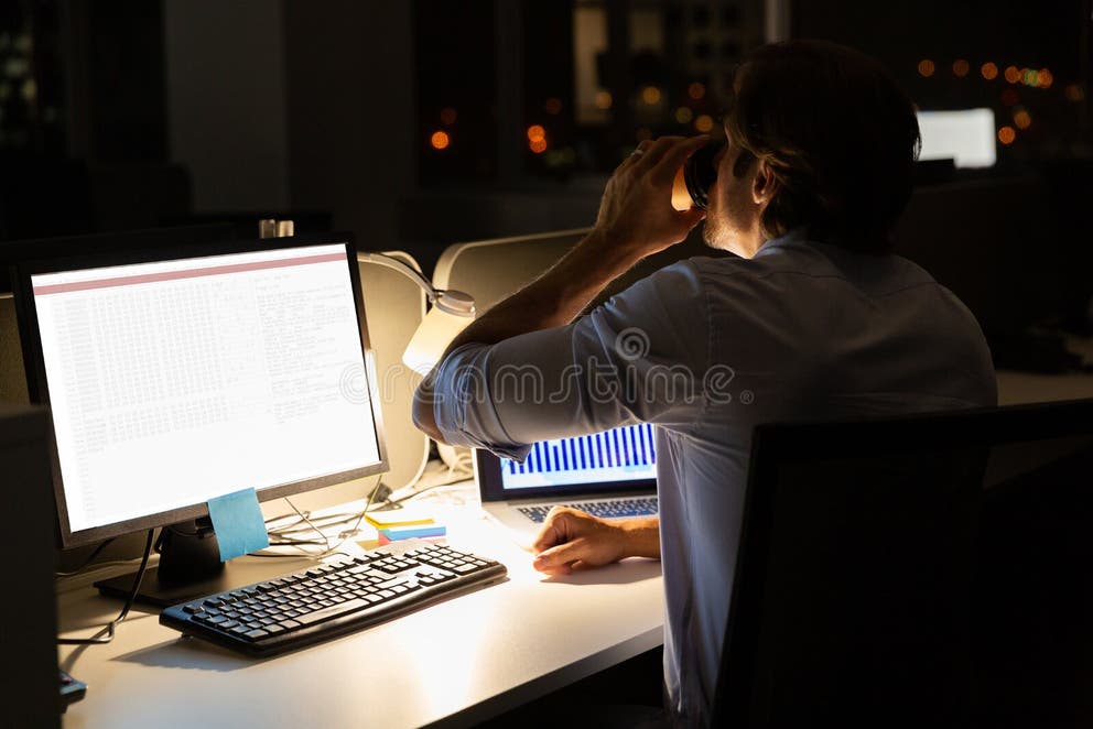 Caucasian Male Programmer Sitting at Desk, Drinking Coffee, Using Computer with Coding on Screen ...