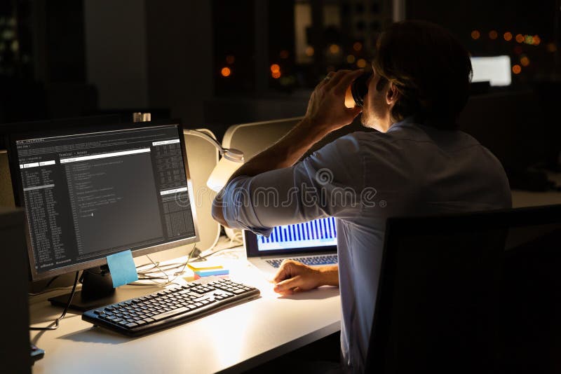 Caucasian Male Programmer Sitting at Desk, Drinking Coffee, Using Computer with Coding on Screen ...
