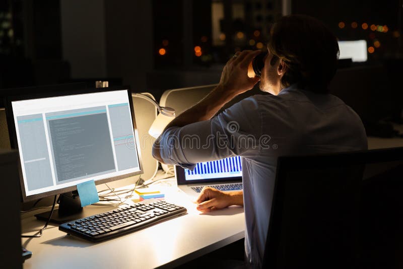 Caucasian Male Programmer Sitting at Desk, Drinking Coffee, Using Computer with Coding on Screen ...