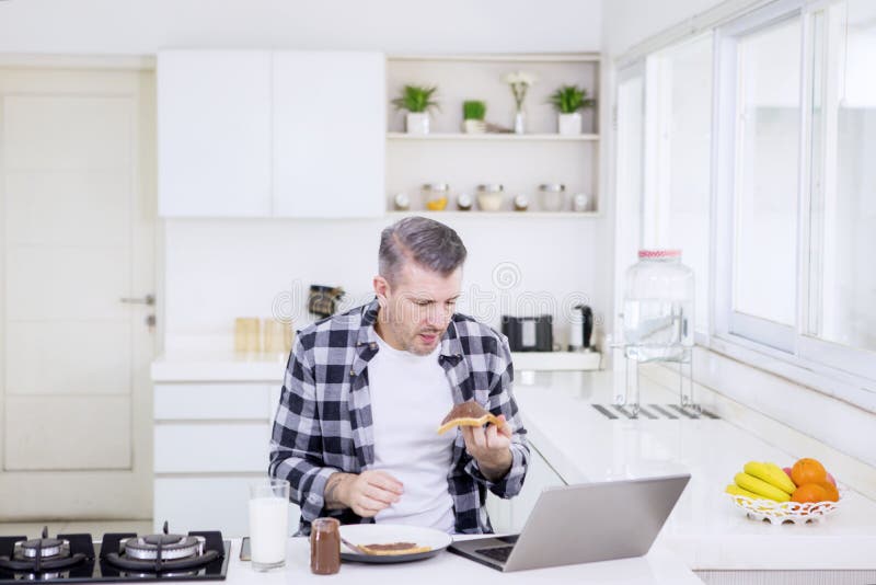 Caucasian Man Eating Breakfast while Working Stock Photo - Image of ...