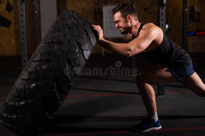 Caucasian Man Pushing a Car Tire in the Gym. Stock Photo - Image of ...