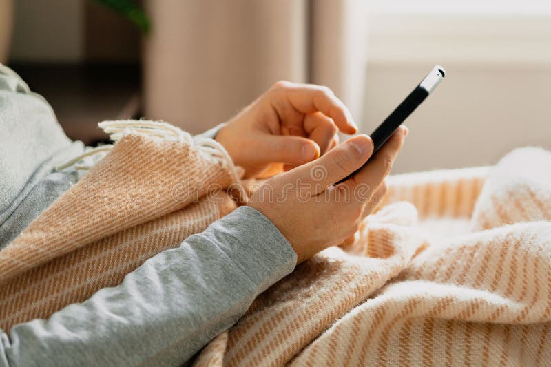 A Caucasian Man Relaxing, Using Smart Phone Lying in Bed Under Throw at ...