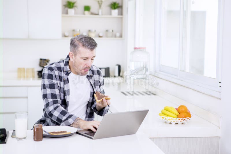 Caucasian Man Uses a Laptop during Breakfast Stock Image - Image of ...