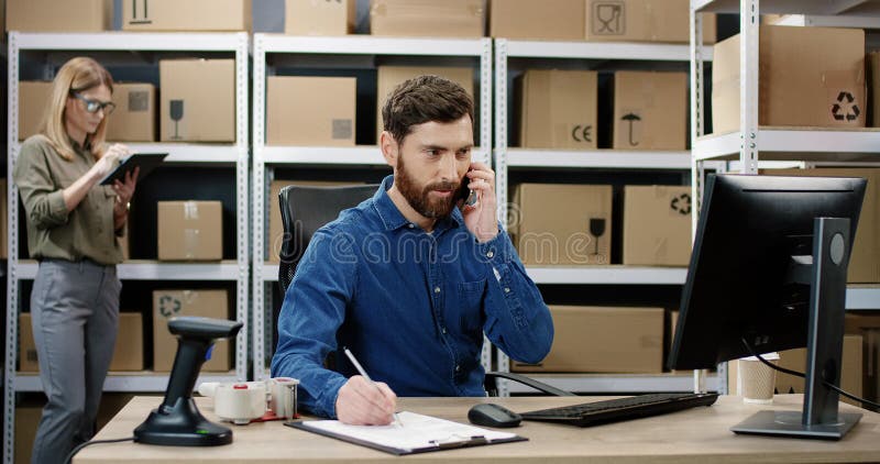 Caucasian Postman Working at Computer in Post Delivery Office and ...