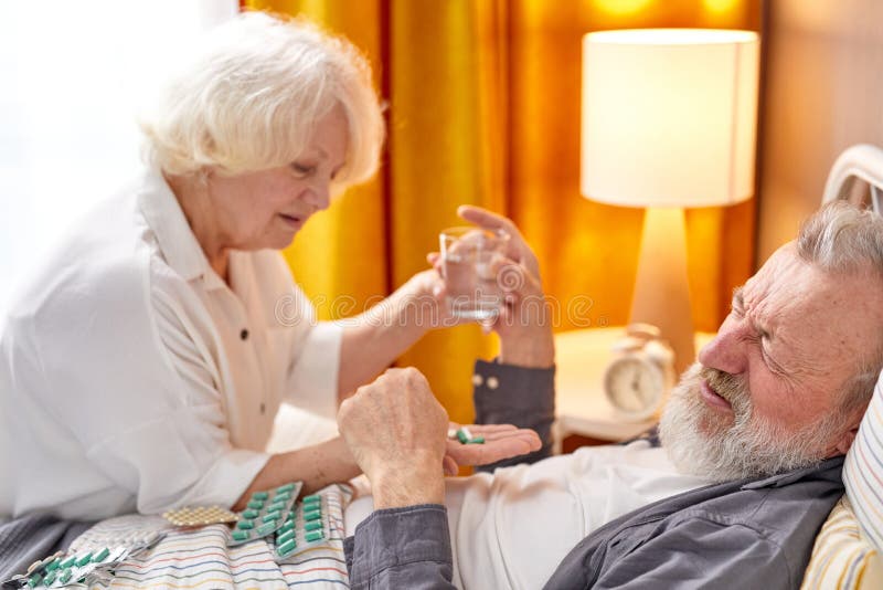 Caucasian Senior Man Taking Medicines And Drinking Water While Lie On