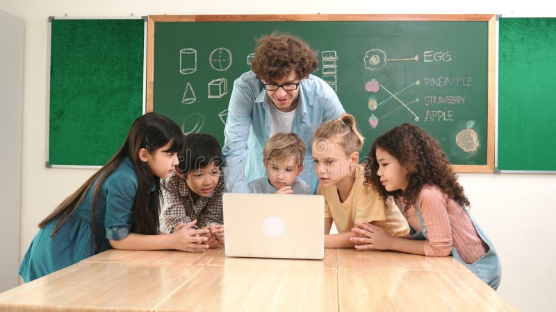 Caucasian Teacher and Diverse Student Looking at Laptop at Classroom ...