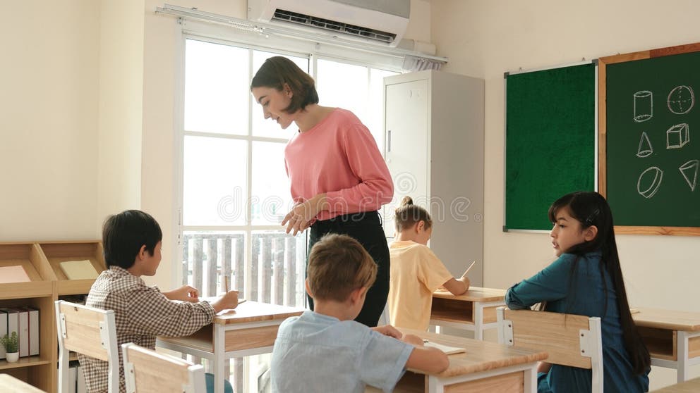 Caucasian Teacher Walking and Check Student Homework at Classroom ...