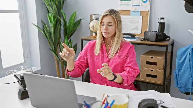 Caucasian Woman in Pink Blouse Multitasking in a Modern Office, Using a ...