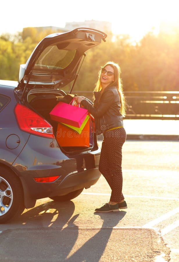 Caucasian Woman Putting Her Shopping Bags Into The Car Trunk Stock