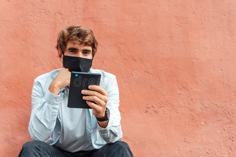 Caucasian Young Man Looking at the Camera, Wearing a Mask and Reading ...