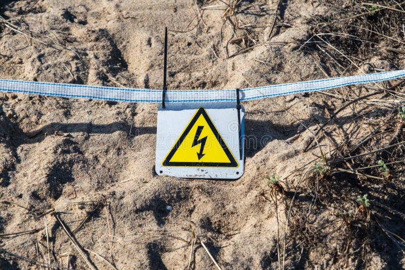 Cautionary Electrical Hazard Sign Placed on Sandy Ground. Stock Image ...