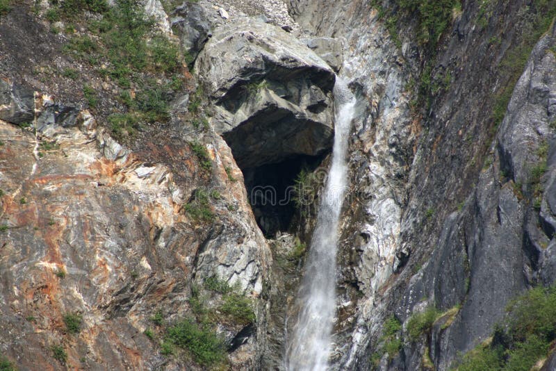A Cave in the Side of the Cliff on One Side of a Small Waterfall Stock ...