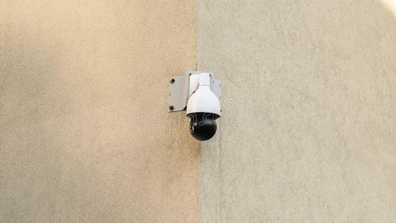 A CCTV Camera Hangs on a Street Lamppost Against a Backdrop of Green ...