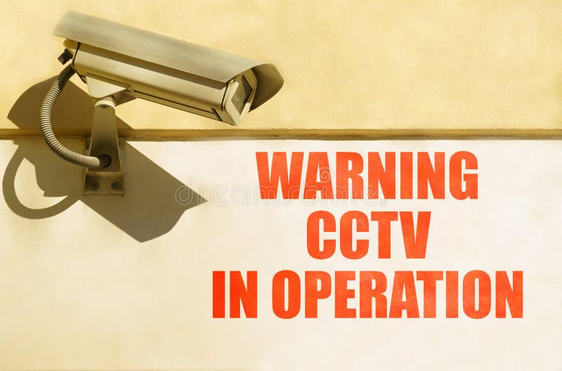 A CCTV Camera is Installed on the Wall of the Building, Next To it is ...