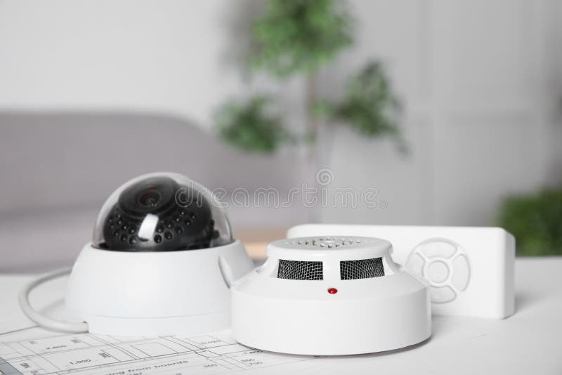 CCTV Camera, Remote Control, Smoke Detector and Building Plan on Table ...