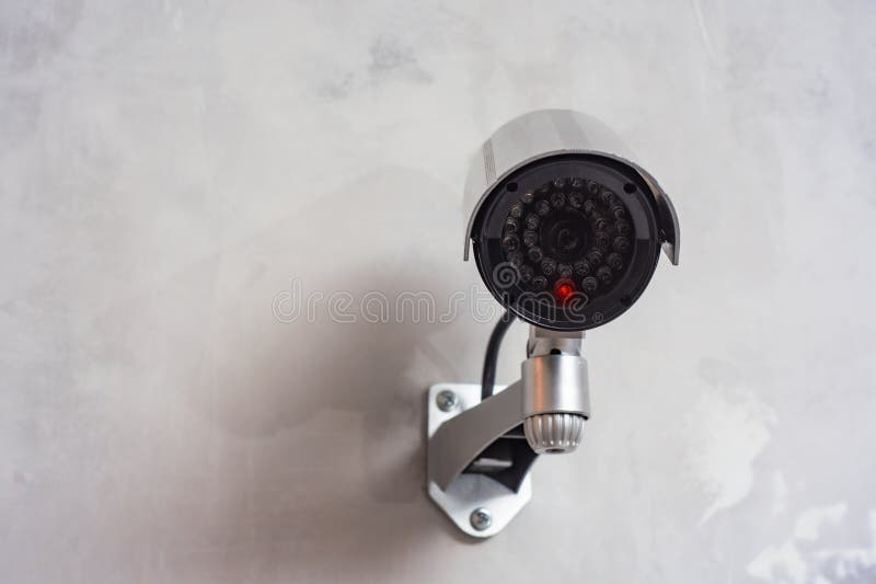 CCTV Security Camera with a Glowing Red Light is Mounted on a Gray Wall ...