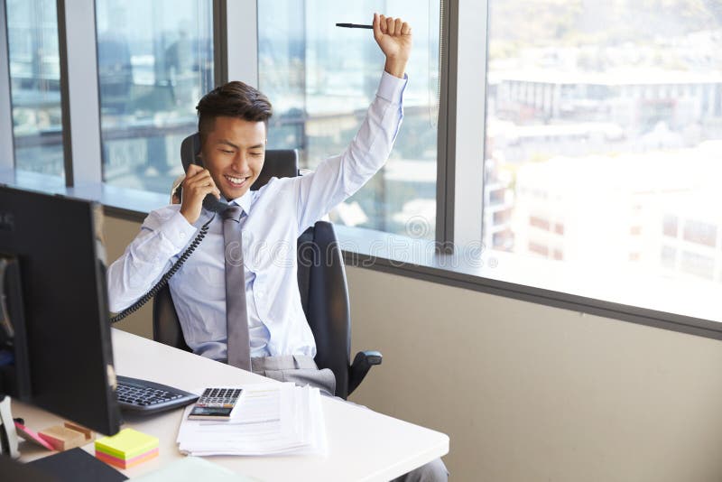 Celebrating Businessman Making Phone Call at Desk in Office Stock Image ...