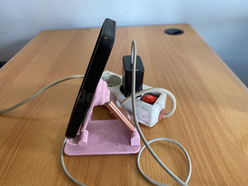 Cell Phone Being Charged on a Brown Table Stock Photo - Image of phone ...