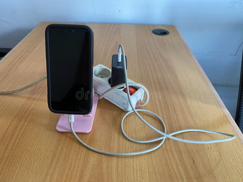 Cell Phone Being Charged on a Brown Table Stock Photo - Image of phone ...