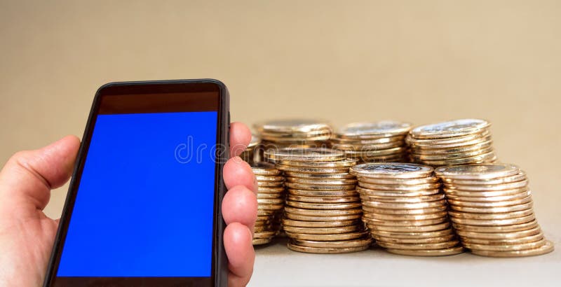 Cell Phone with a Blue Screen in Hand and a Background with Stacks of ...