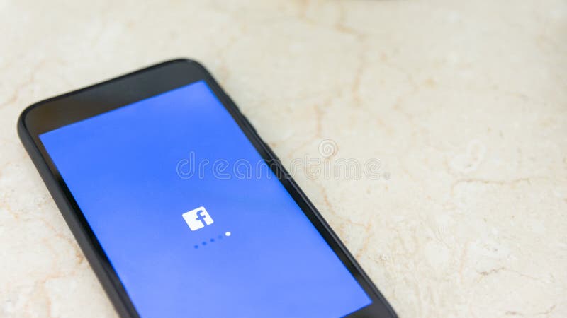 Cell Phone with Facebook App Opening, Showing Logo and Loading Screen ...