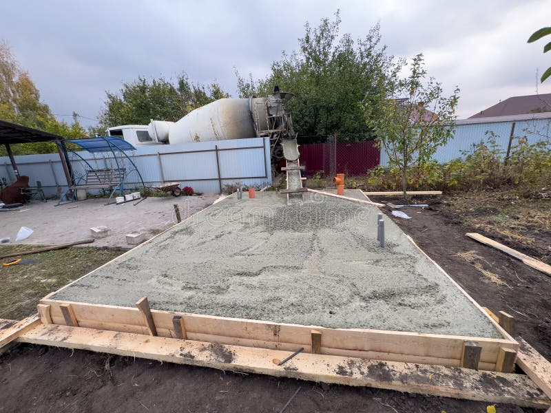 A Cement Mixer is Pouring Concrete into a Hole in the Ground Stock ...
