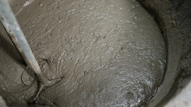 A Builder Mixes Mortar in a Bucket Using a Manual Concrete Mixer. the ...