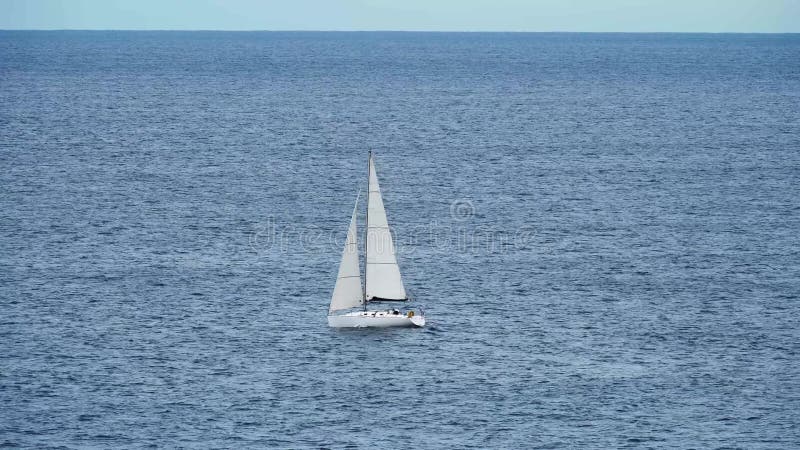 In the Center of the Frame, from Right To Left, a White Sailing Yacht ...