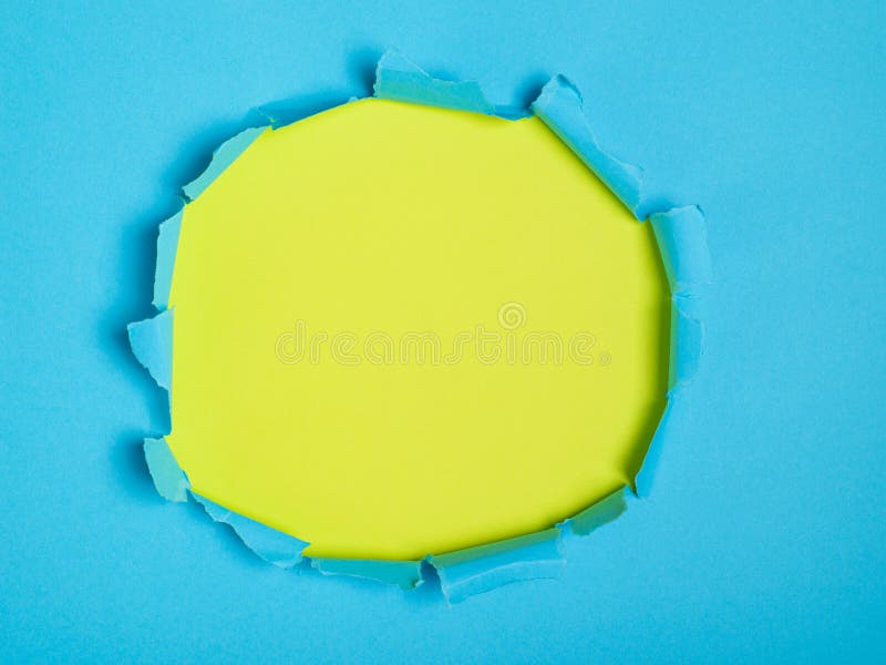 Center Torn Hole in Blue Paper Revealing a Yellow Background. Space for ...