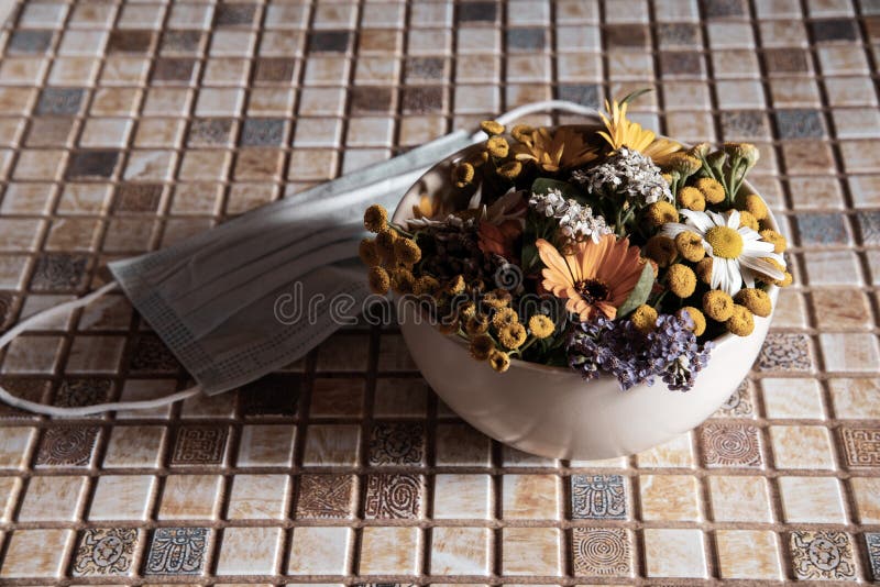 A Ceramic Bowl with Medicinal Herbs and a Protective Medical Mask on ...