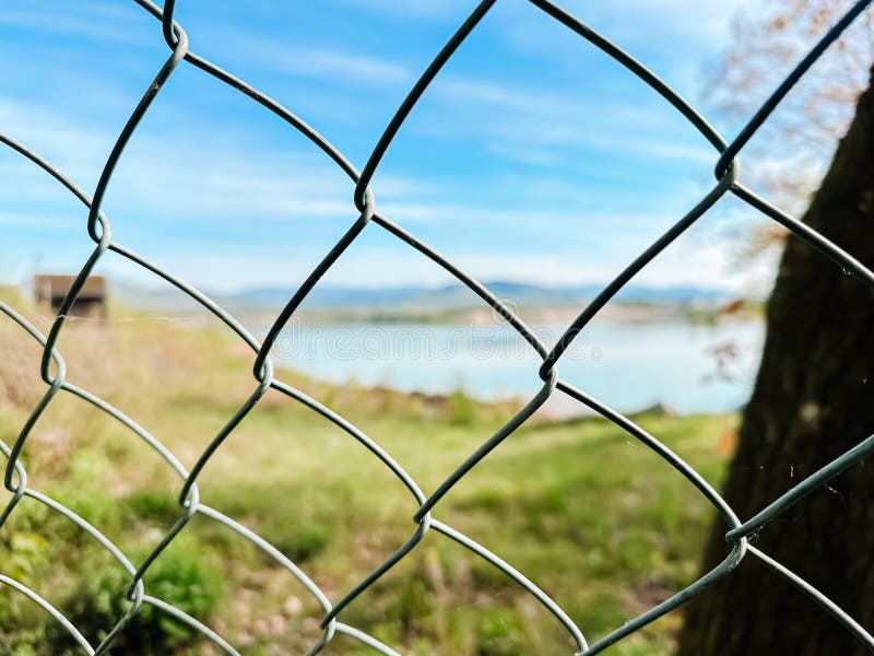 A Chain Link Fence with a View of a Lake Stock Photo - Image of pattern ...