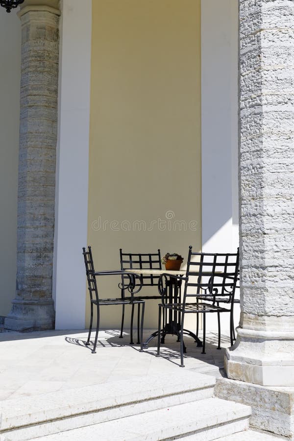 Chairs and Table in Sunlight Behind Pillar Stock Photo - Image of seat ...