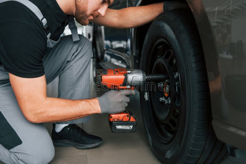 Changing of the Tires. Man in Uniform is Working in the Autosalon at ...