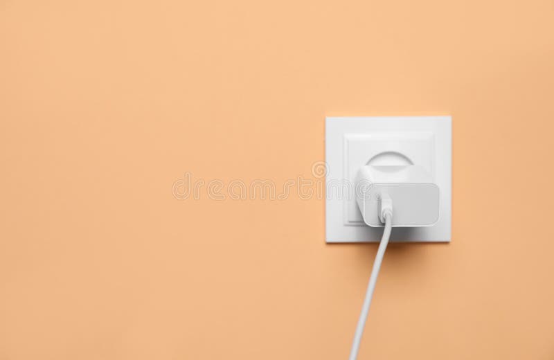 Charger Adapter Plugged into Power Socket on Pale Orange Wall, Space ...