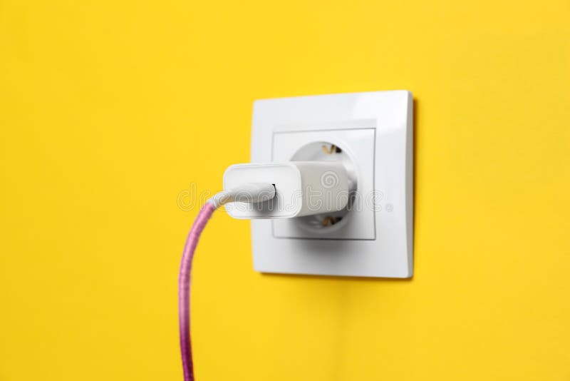Charger Adapter Plugged into Power Socket on Yellow Wall, Closeup ...