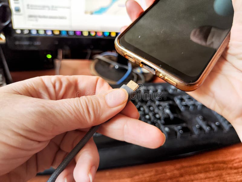 Charging a Cell Phone with a Cable while Working at a Desk with a ...