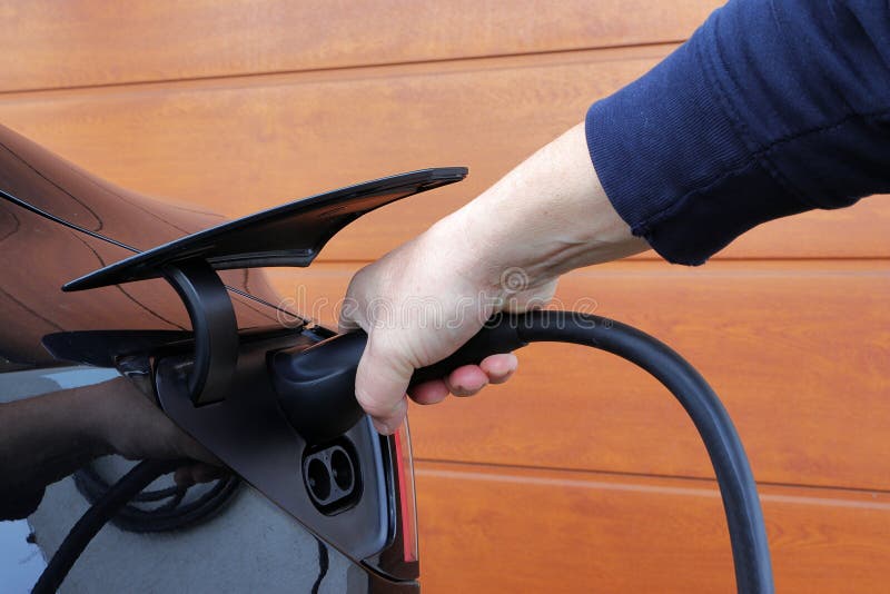 Charging an Electric Car. Hand Holding Charging Cable Stock Photo ...