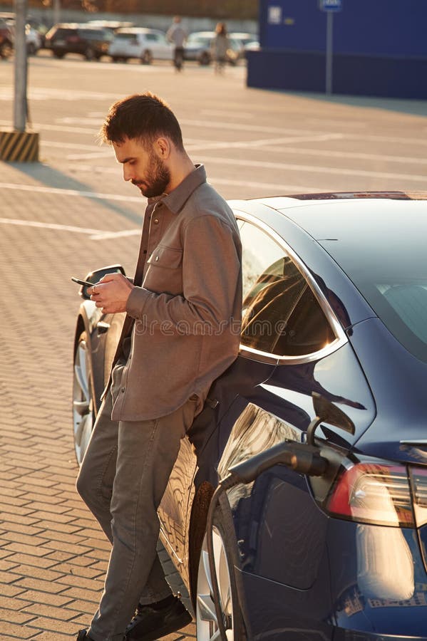 Charging Process. Man is Standing Near His Electric Car Outdoors Stock ...