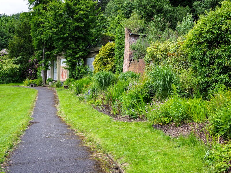 Charming Garden Path Surrounded by Lush Greenery and Rustic Brick Walls ...