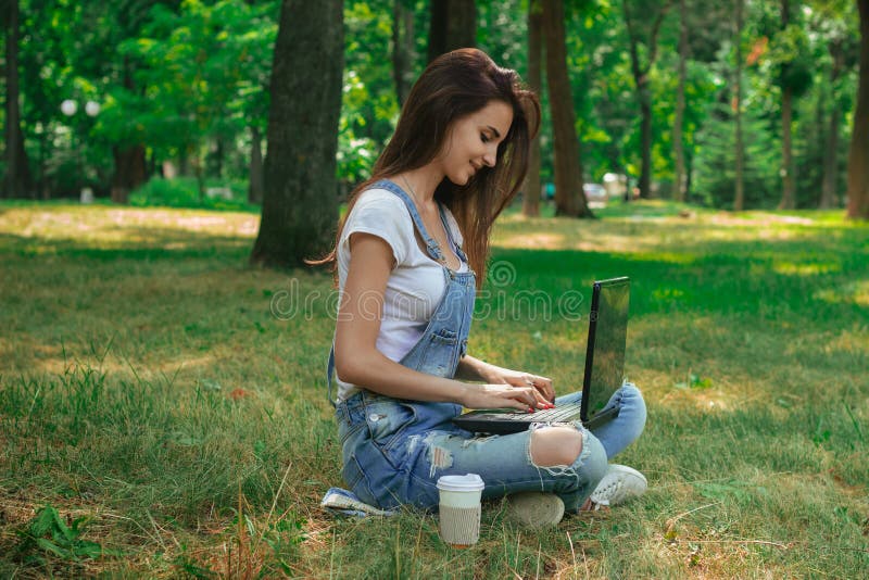 Charming Lady Sitting on the Grass and Prints on a Laptop Stock Image ...
