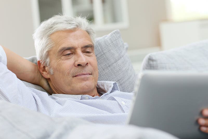 Charming Senior Man Lying on Sofa Using Tablet Stock Image - Image of ...