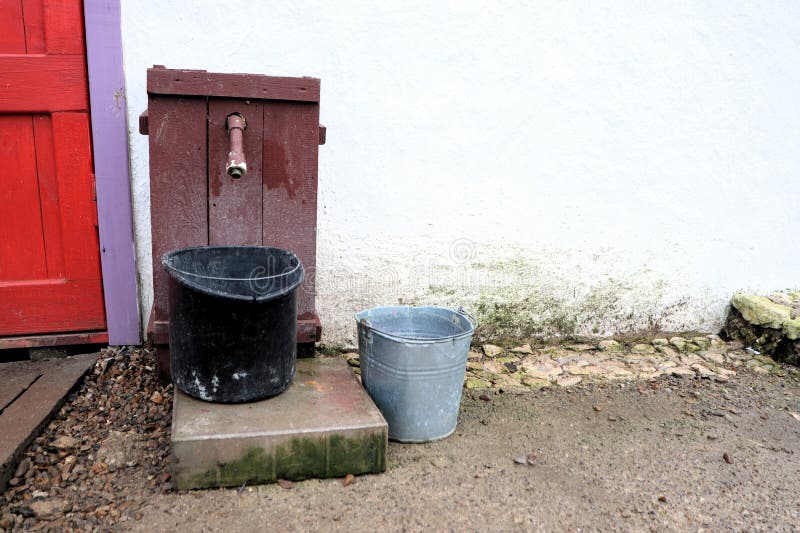 A Water Source with Charming Buckets by a Lovely Red Door that Enhances ...
