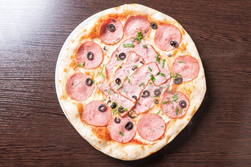 Cheap Pizza with Pepperoni, Ham, Olives and Herbs Stock Photo - Image ...