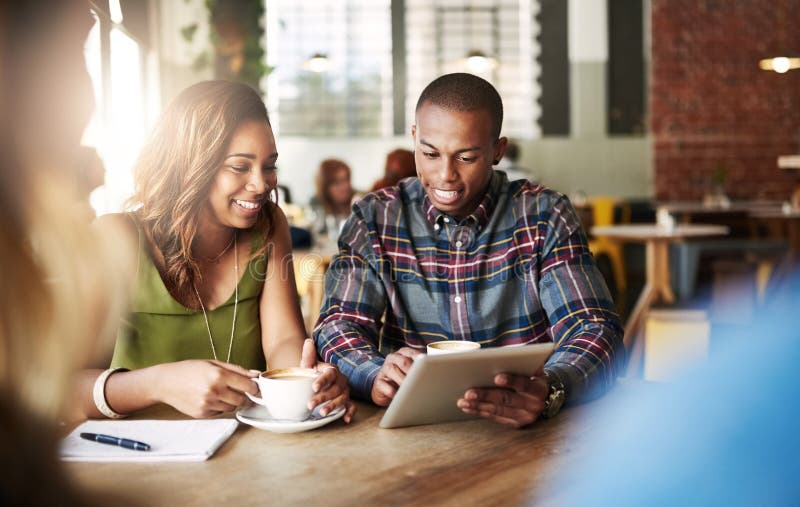 Check this Out. Two Friends Using a Tablet while Having Coffee in a ...