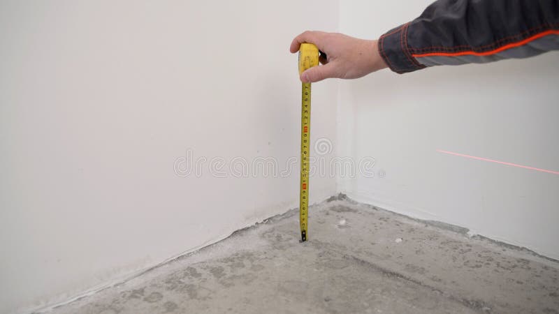 A Worker Inspector Checks the Floor Level with a Metal Ruler at a ...
