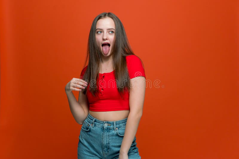 Cheeky Modern Young Girl Showing Tongue Teasing Making Faces Fooling Grimacing On Orange