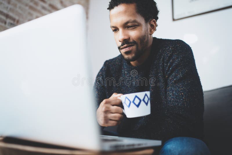 Cheerful African Man Using Computer and Smiling while Sitting on the ...