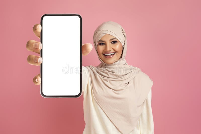 Cheerful Arab Muslim Woman in Hijab Displaying Smartphone with Blank ... Cheerful Arab Muslim Woman in Hijab Displaying Smartphone with Blank ...