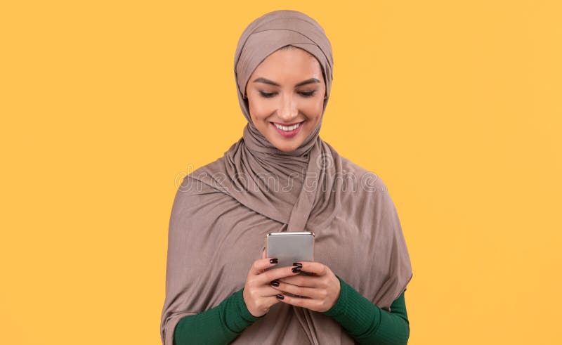 Cheerful Arabic Lady Using Mobile Phone Texting Standing in Studio ...