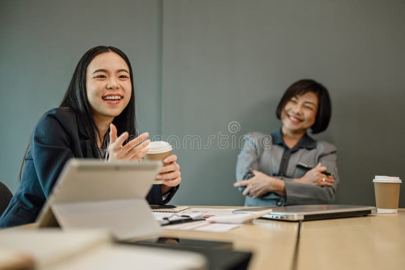 Cheerful Asian Female Manager Talking To Colleagues during Break at ... Cheerful Asian Female Manager Talking To Colleagues during Break at ...